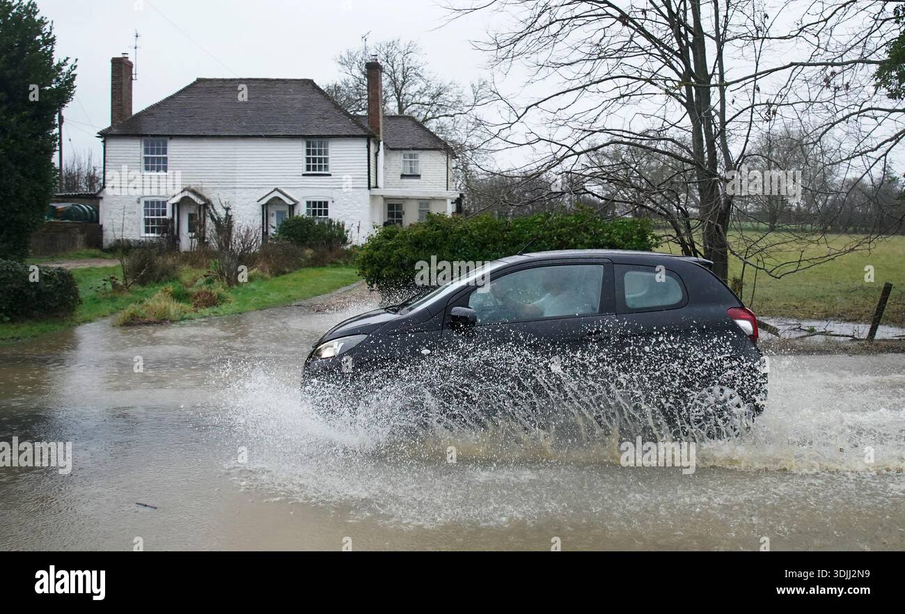 A car passes through a flooded road in Ashford, Kent. Storm Chandra ...