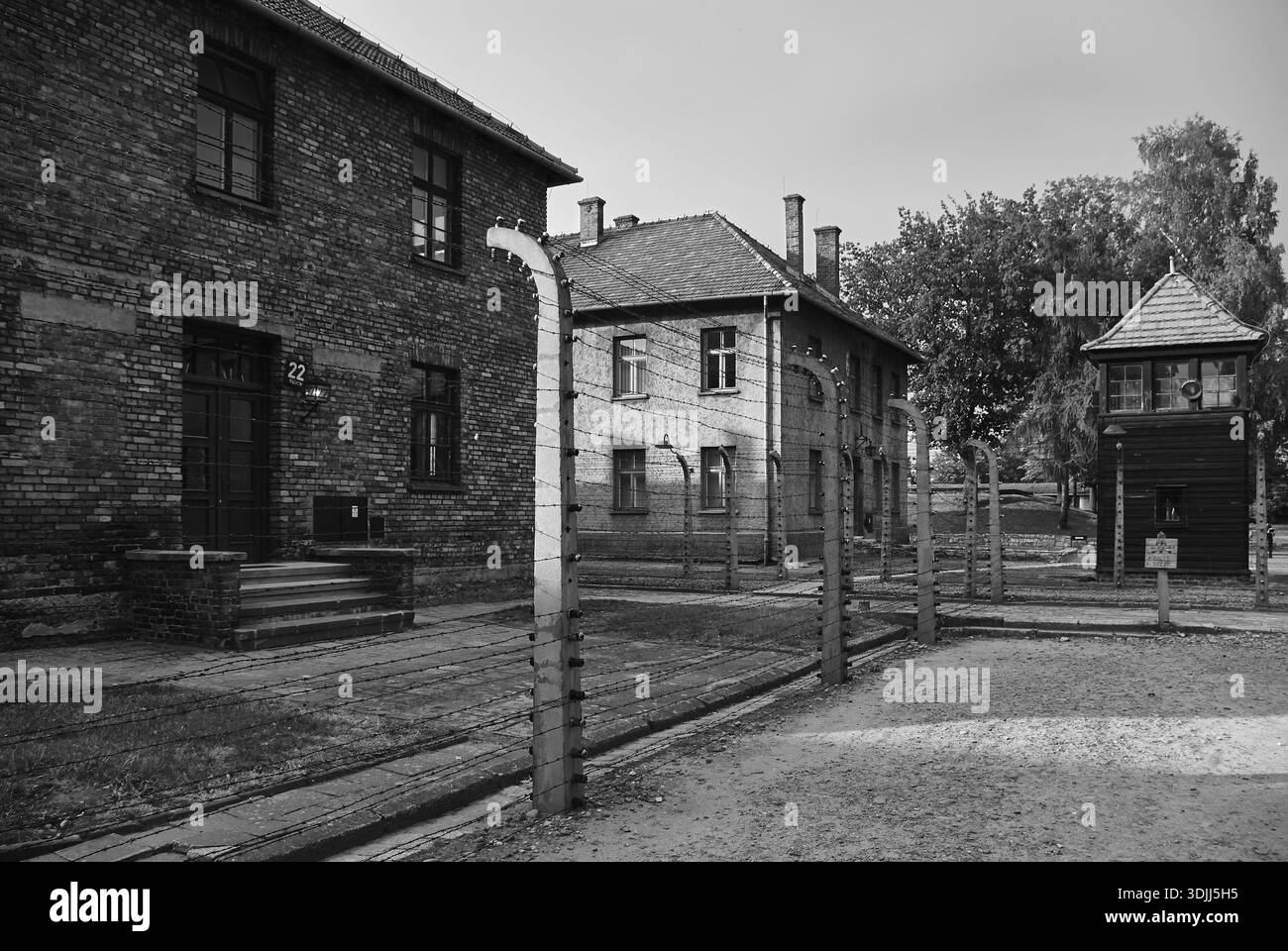 Brick barracks and guard tower behind wire fence at Auschwitz Stock ...