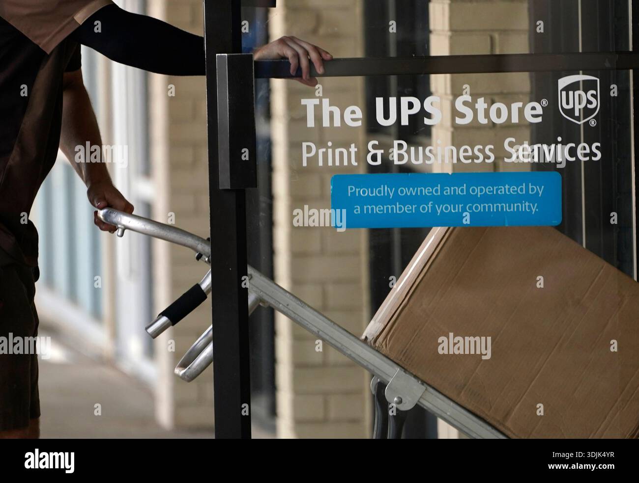 FILE - A UPS driver enters a United Parcel Service store with packages ...