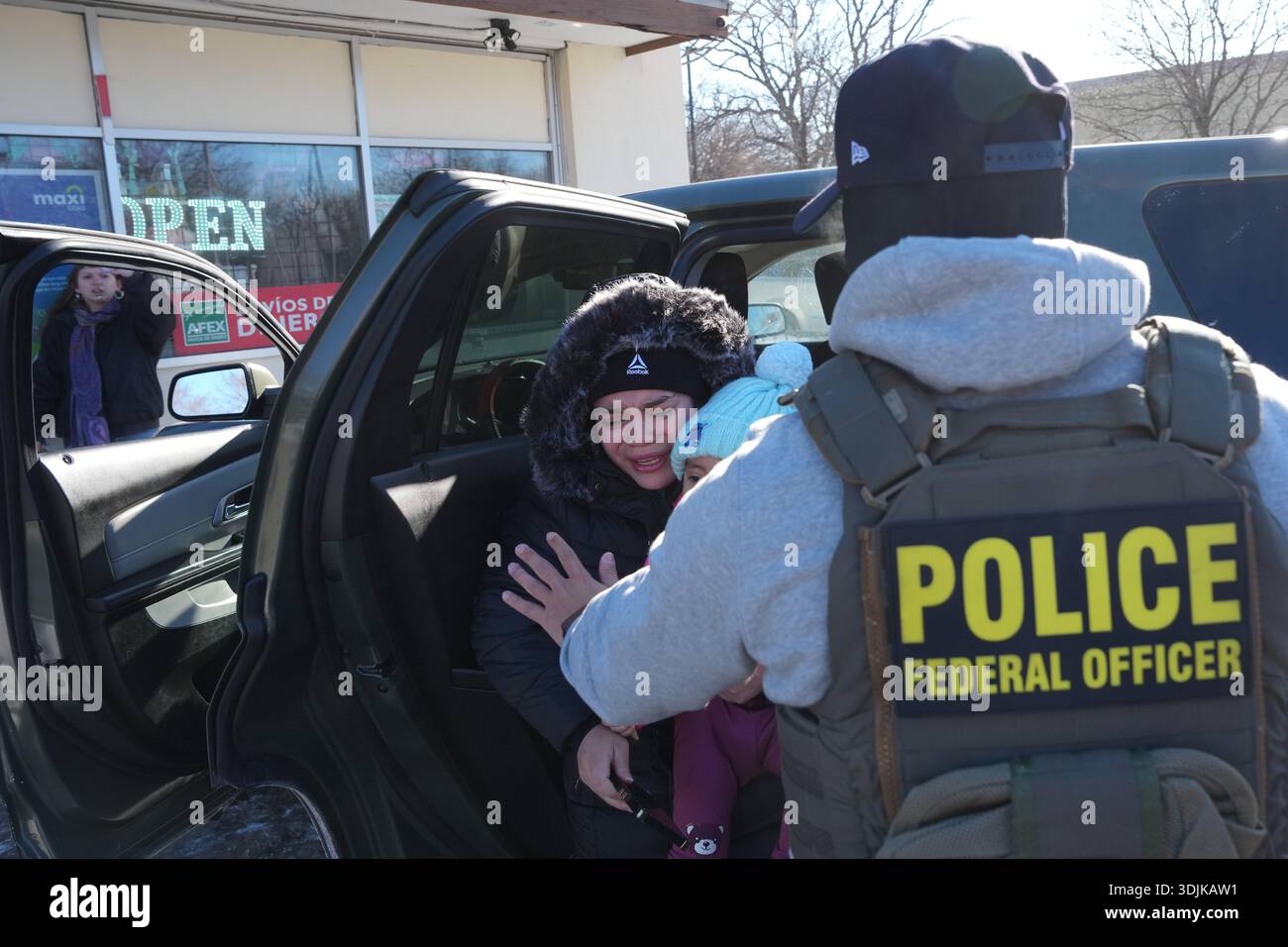 A woman holding a child gets into federal immigration officer's vehicle ...