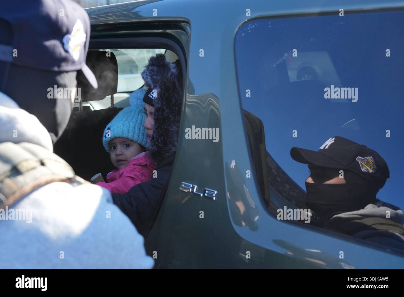 A woman holding a child gets into federal immigration officer's vehicle ...