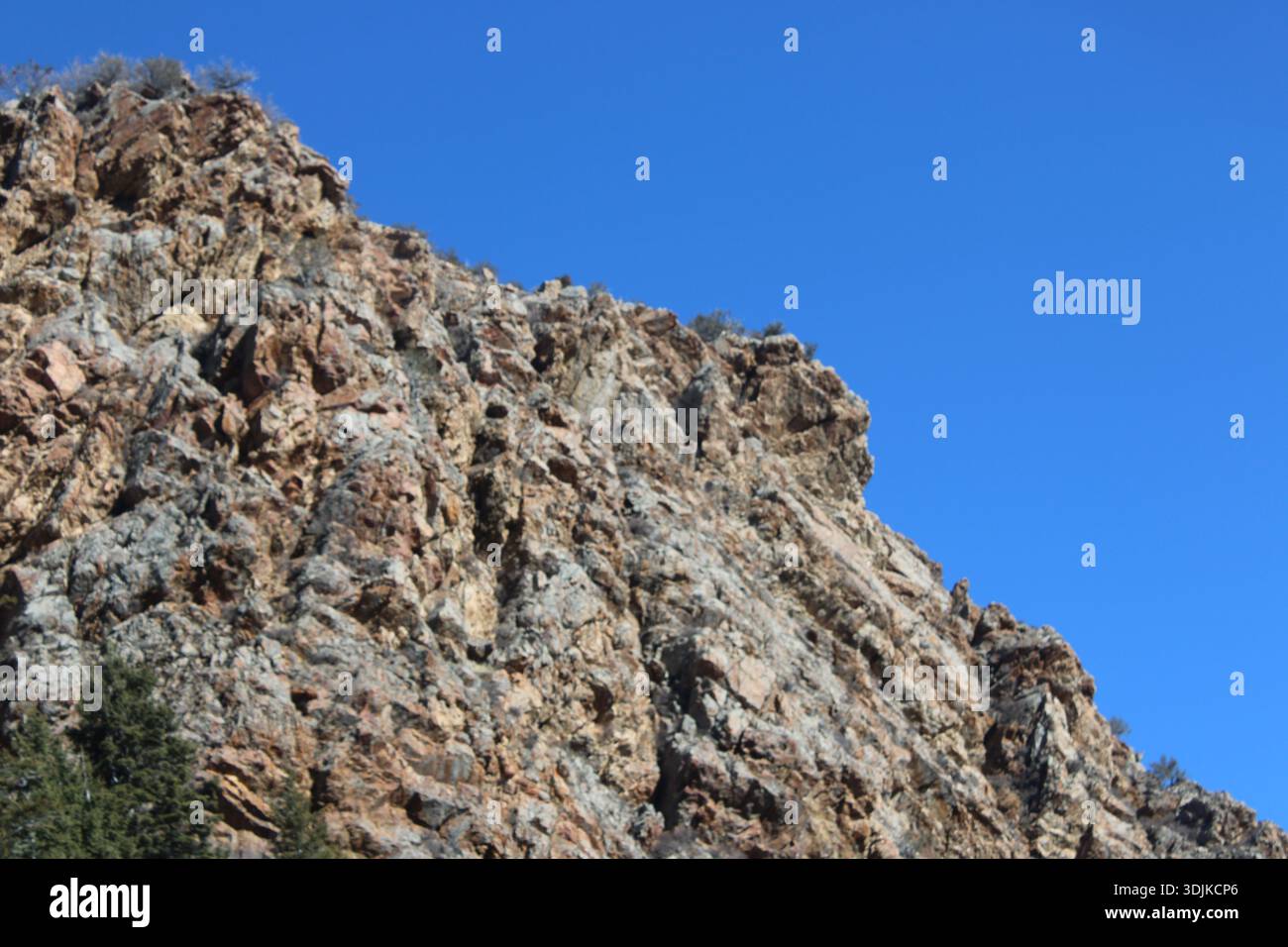 Steep rocky cliff face with rugged stone textures rising against a ...
