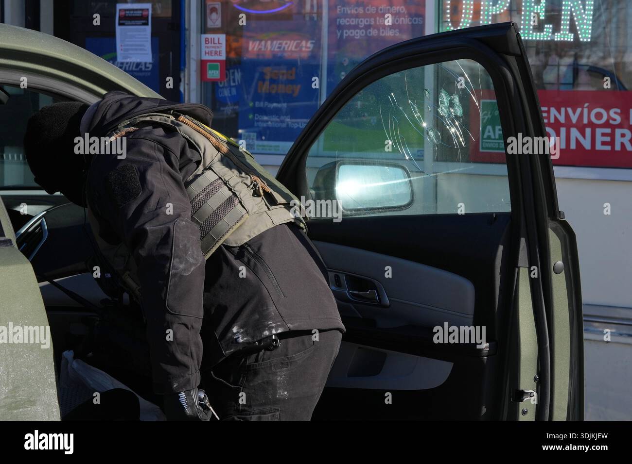 Federal agents look inside a vehicle after a man is detained by federal ...