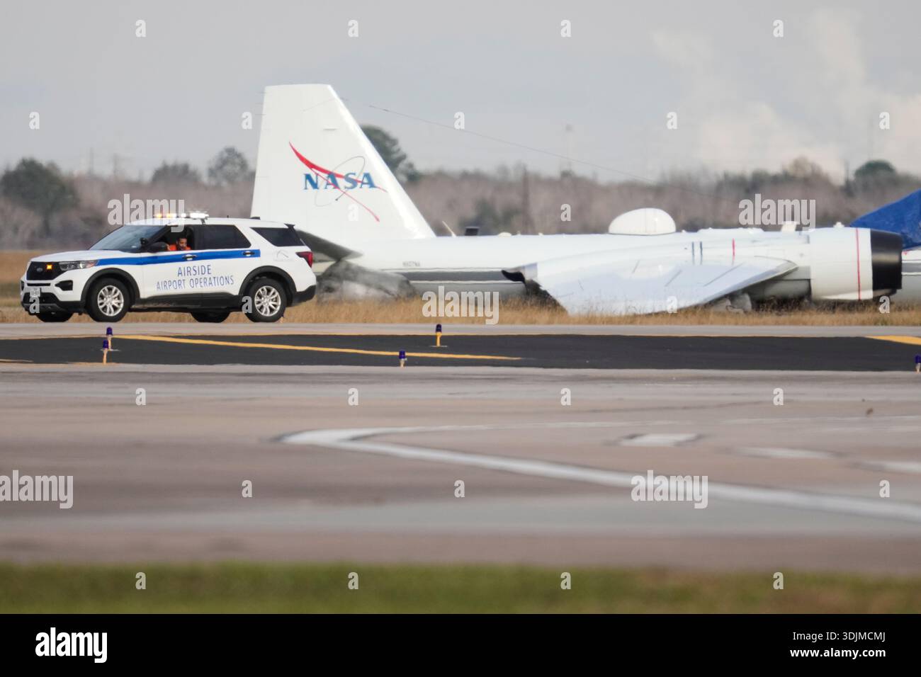A NASA aircraft sits near a runway at Ellington Airport after making a ...