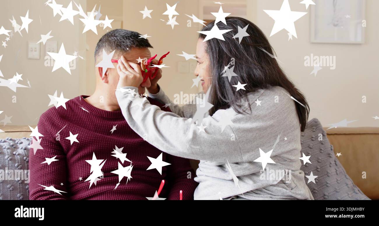 Holding red flower, couple wearing gray and burgundy sitting on beige ...