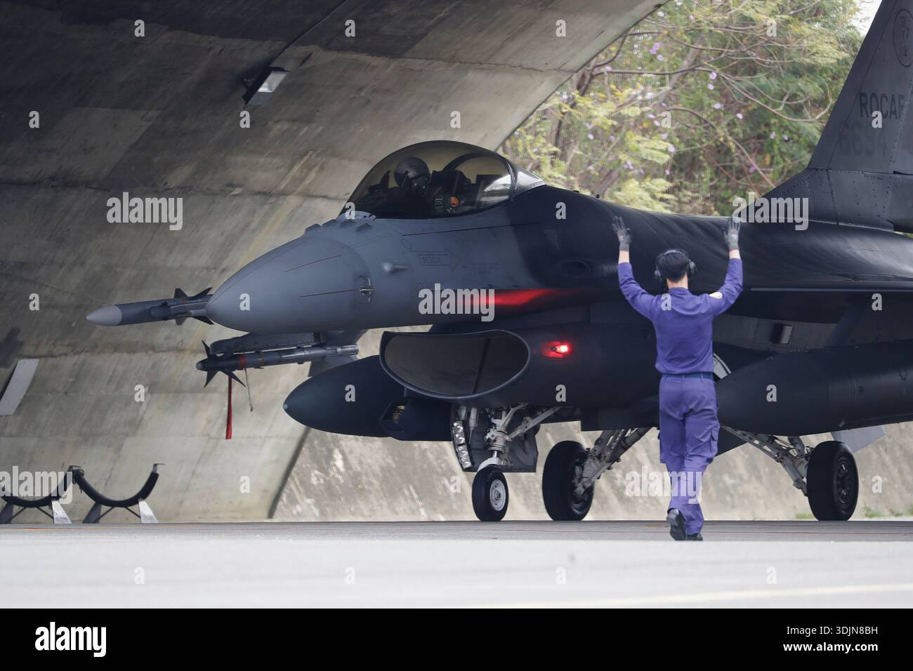 A ground personnel guards a Taiwan air force F-16V fighter jet to taxi ...