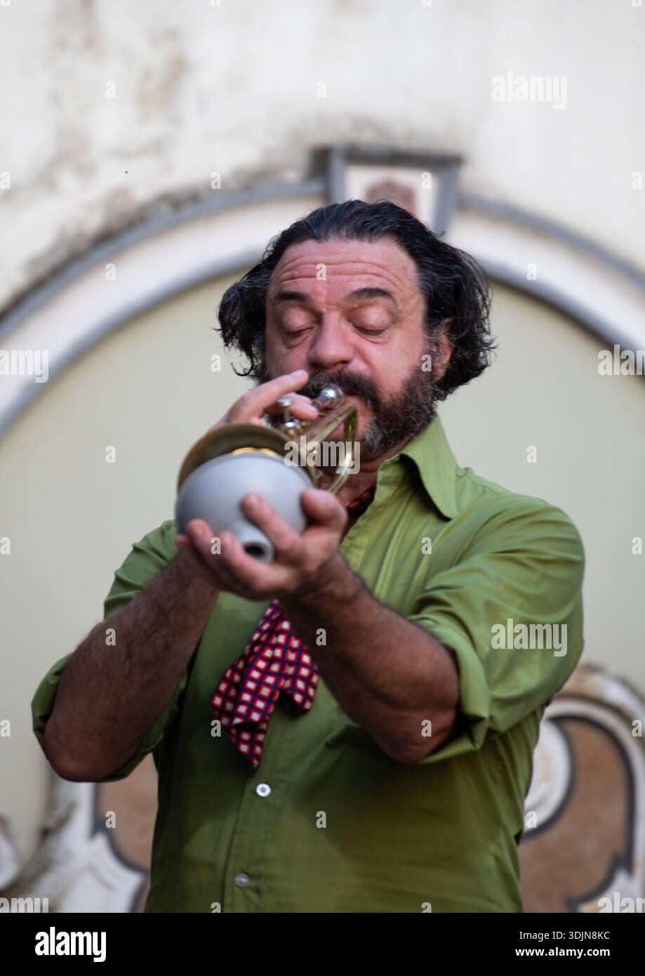 Professional male musician playing a brass trumpet with a plunger mute ...