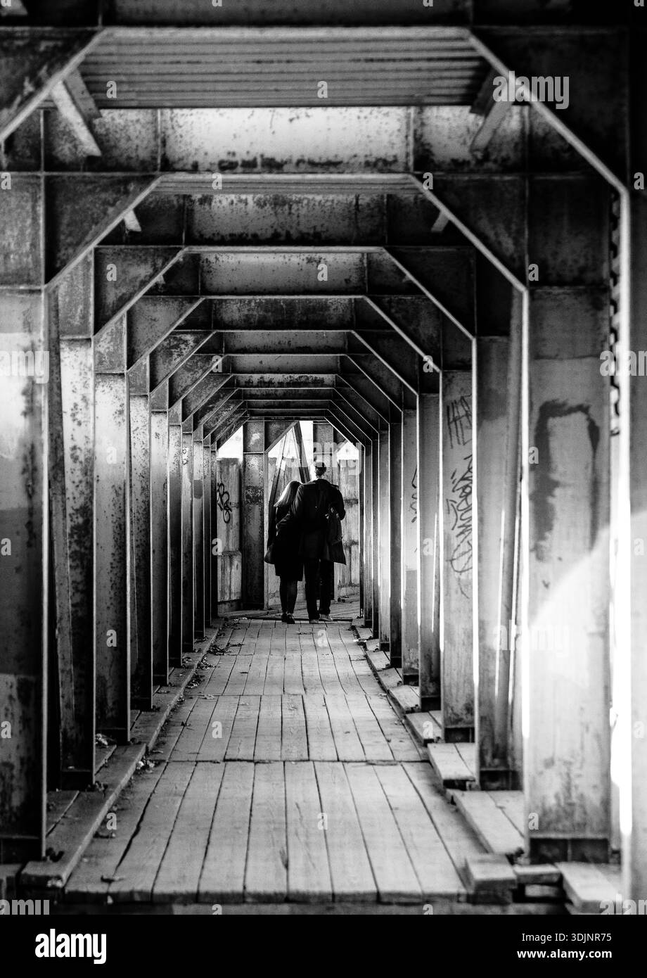 Two people walking through a covered pedestrian passageway with wooden ...