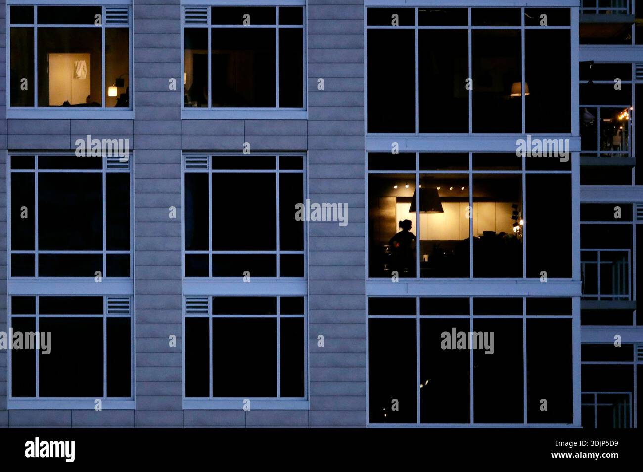 FILE - A person looks out of a window in an apartment building in ...