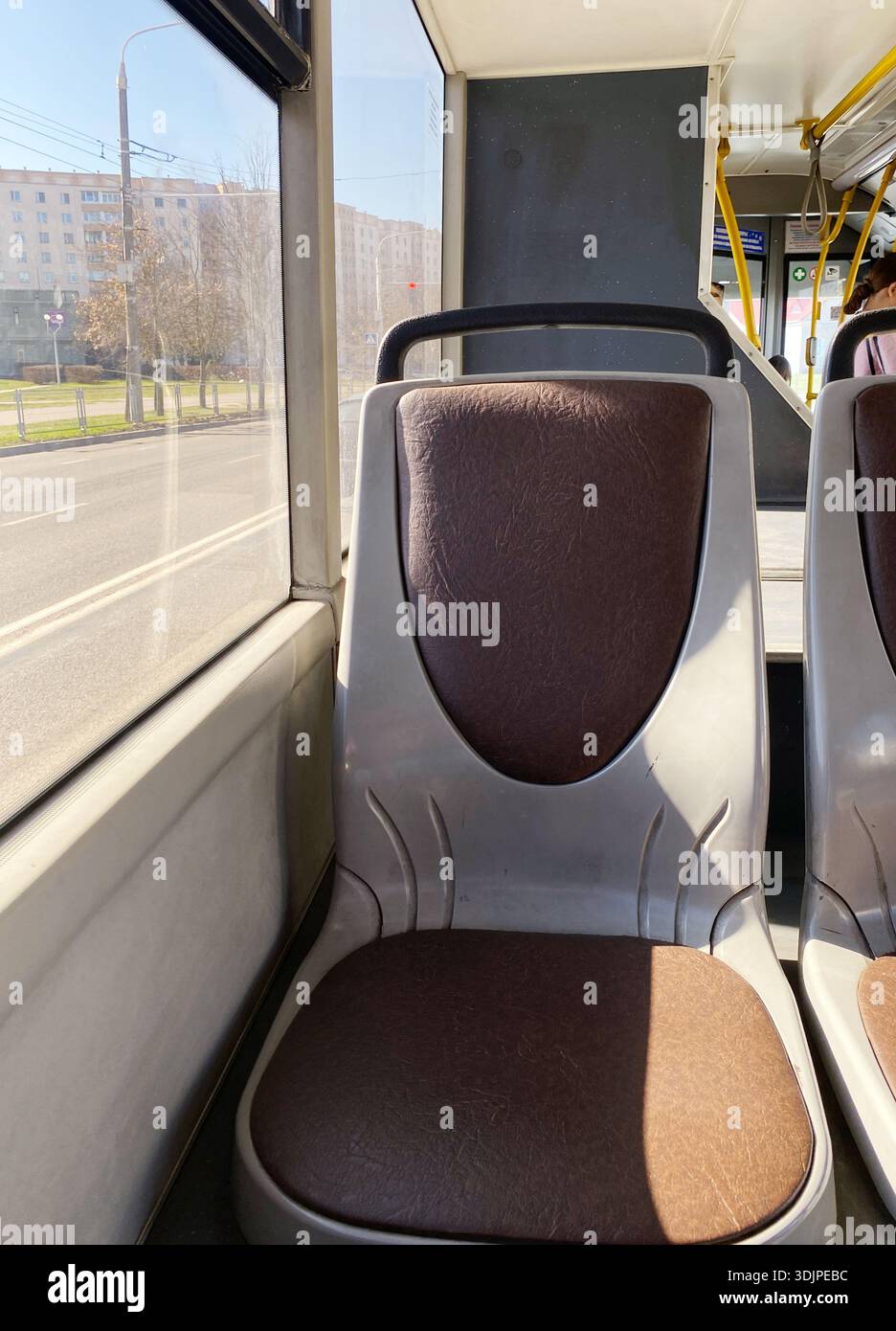 An empty bus seat featuring brown upholstery, illuminated by sunlight ...