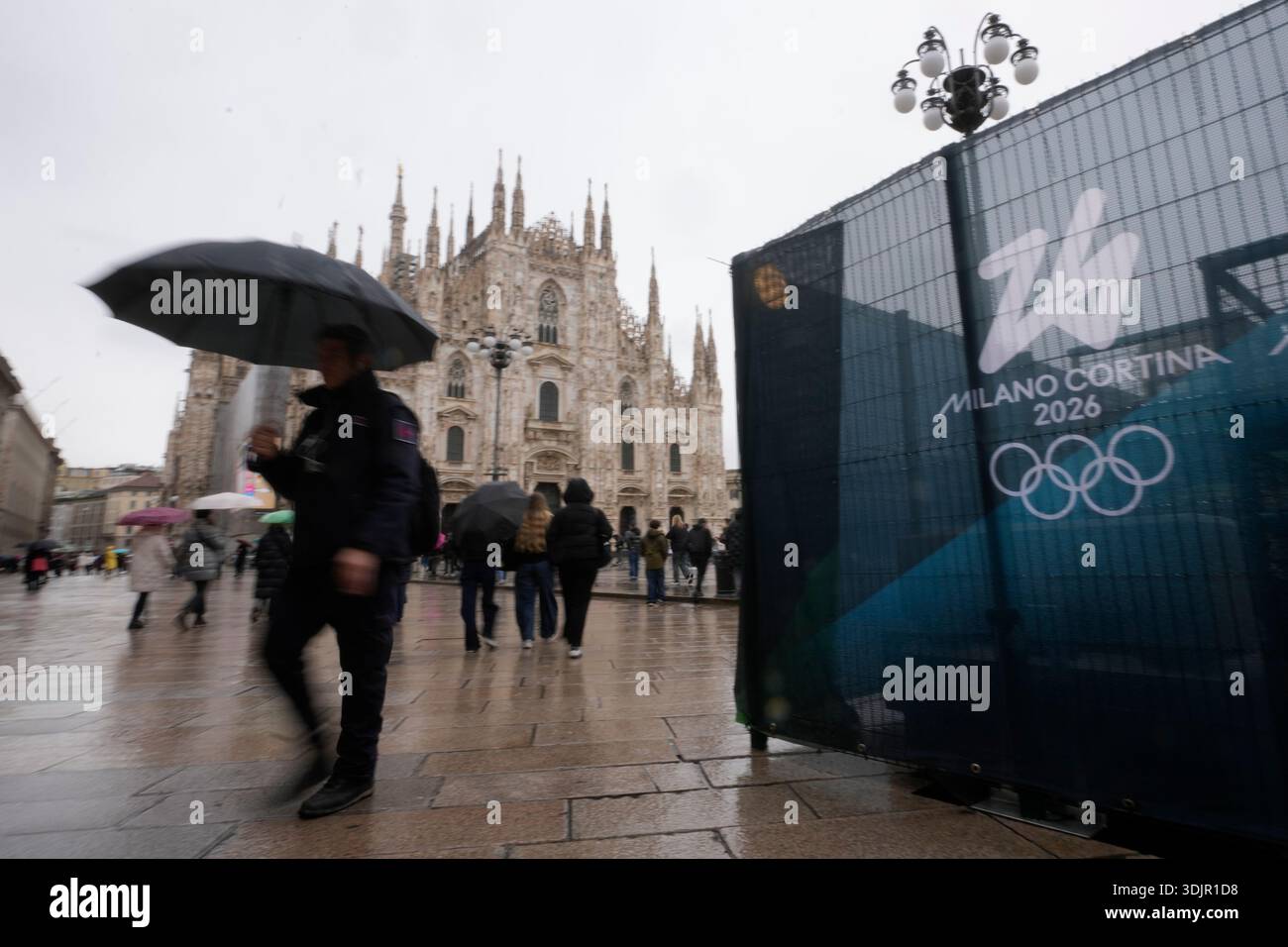 People walk in the rain in front of the Duomo gothic cathedral, in ...