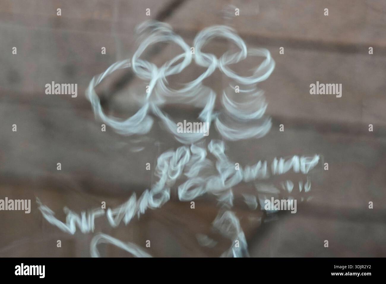 The Milan Cortina Winter Olympic rings are reflected in a puddle, in ...