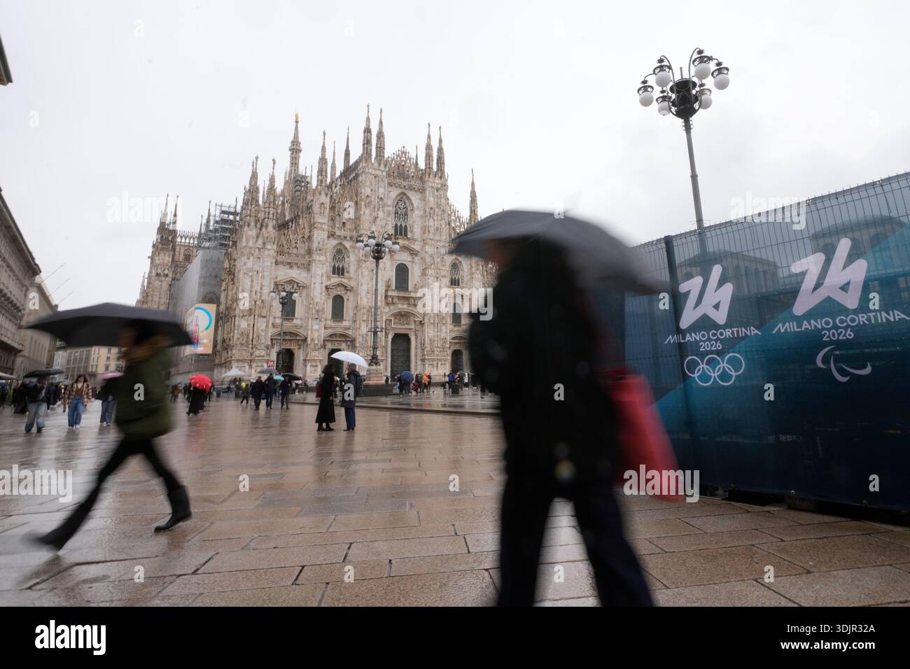 People walk in the rain in front of the Duomo gothic cathedral, in ...