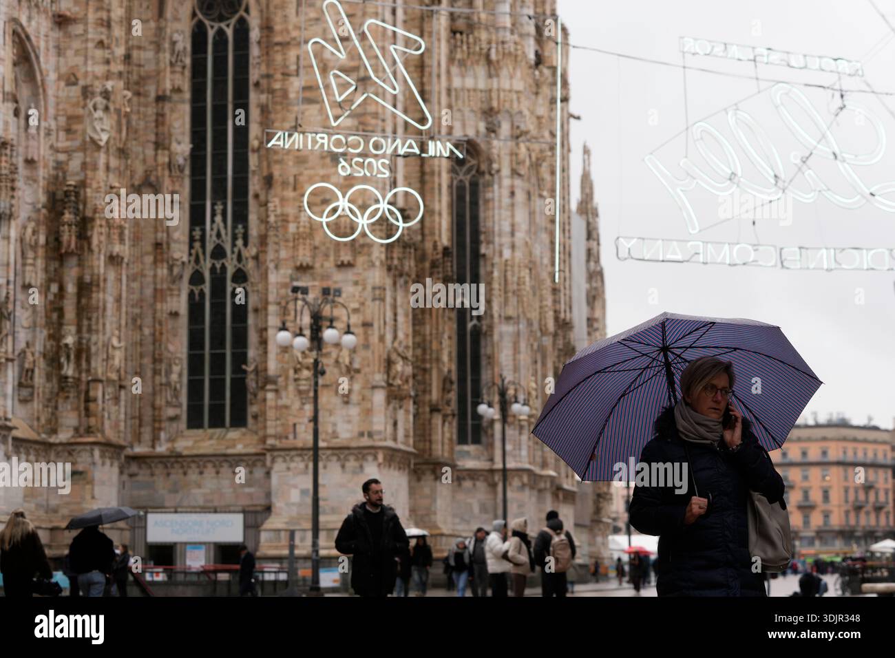 People walk in the rain in front of the Duomo gothic cathedral, in ...