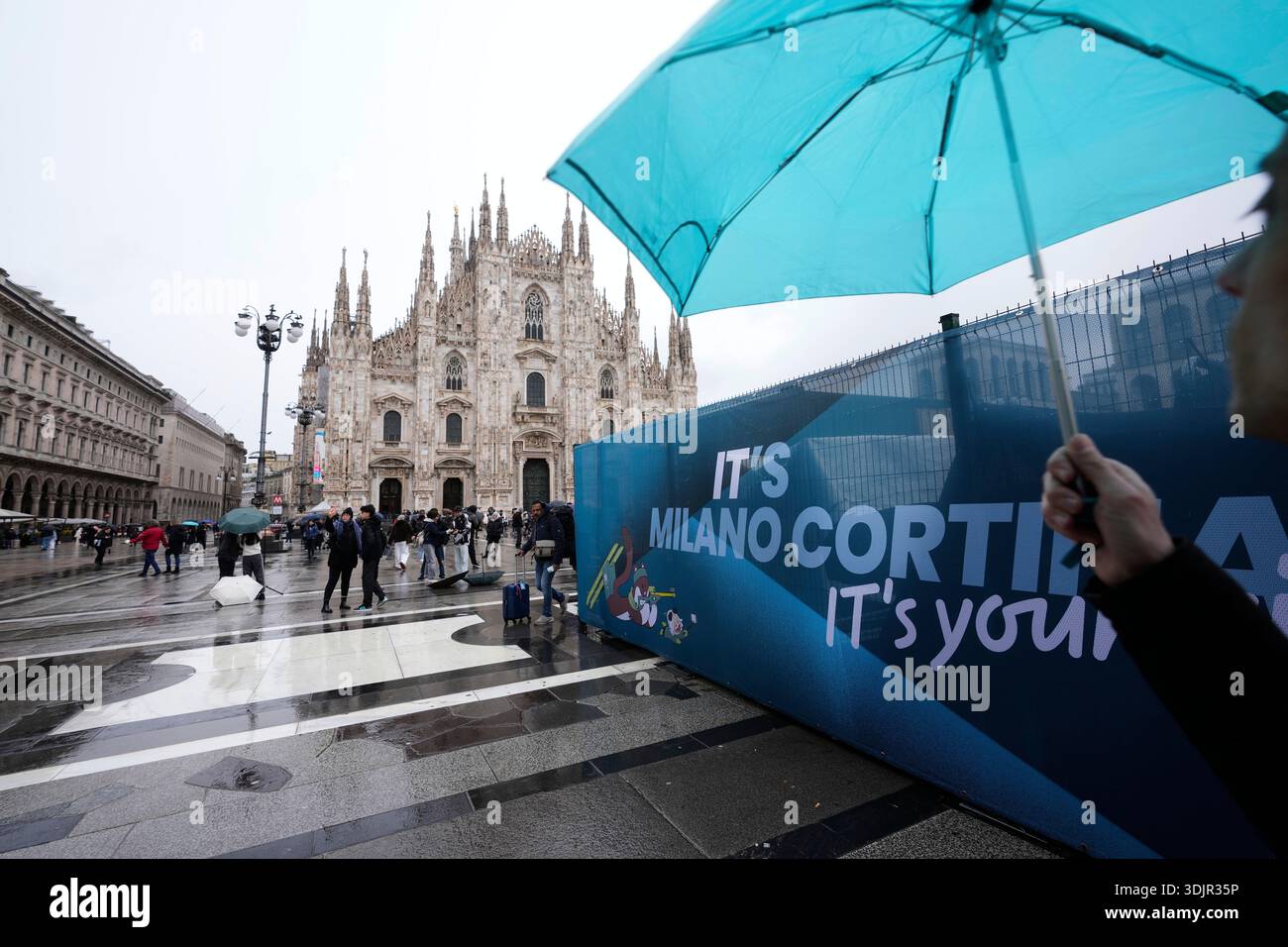 People walk under the rain in front of the Duomo gothic cathedral, in ...