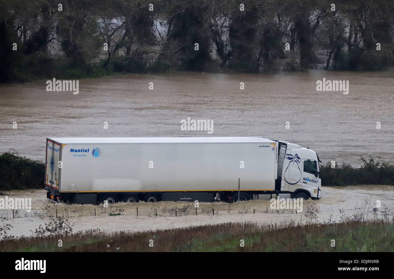 A lorry drives with water covering its wheels along the flooded banks ...