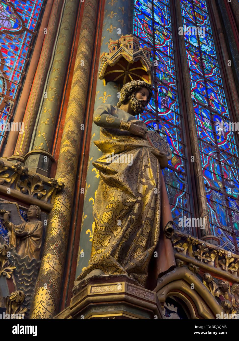 Wooden sculpture of one of the 12 apostles and stained glass windows of ...