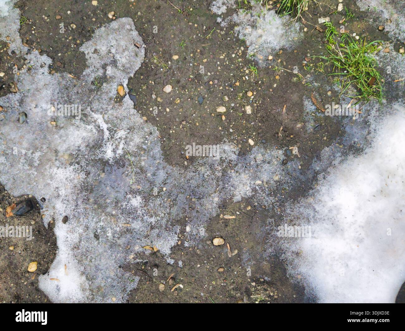 Top down view of melting snow and ice on a muddy urban surface at Ors ...