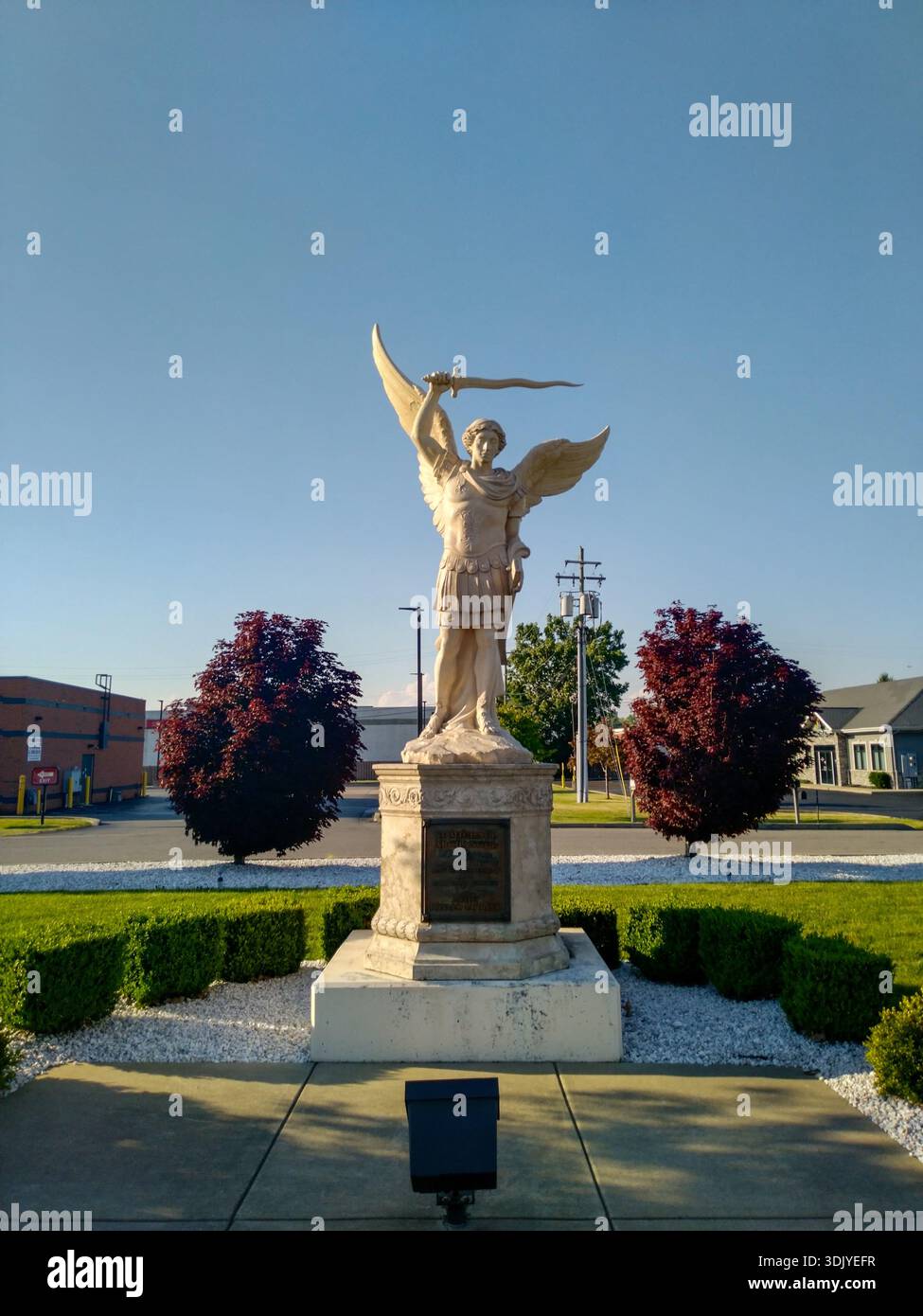 Stone archangel statue holding sword standing in symmetrical landscaped ...
