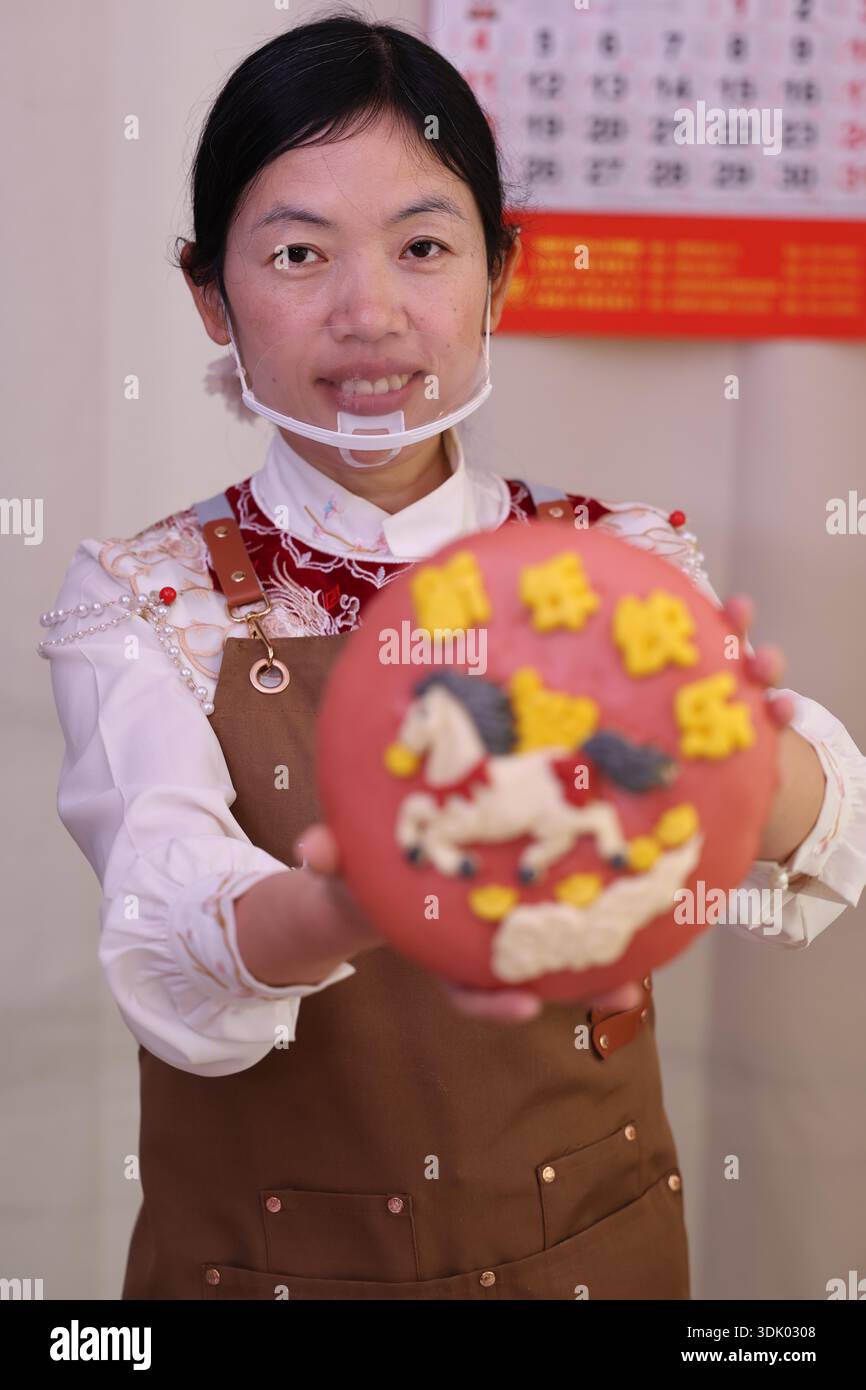 A worker displays freshly steamed traditional flower buns at a heritage ...
