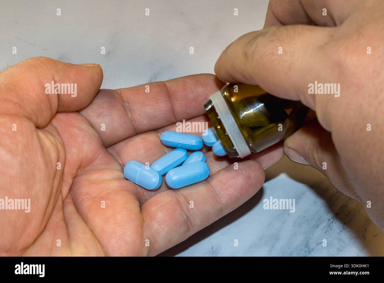 hand pouring blue pills from bottle into palm Stock Photo - Alamy
