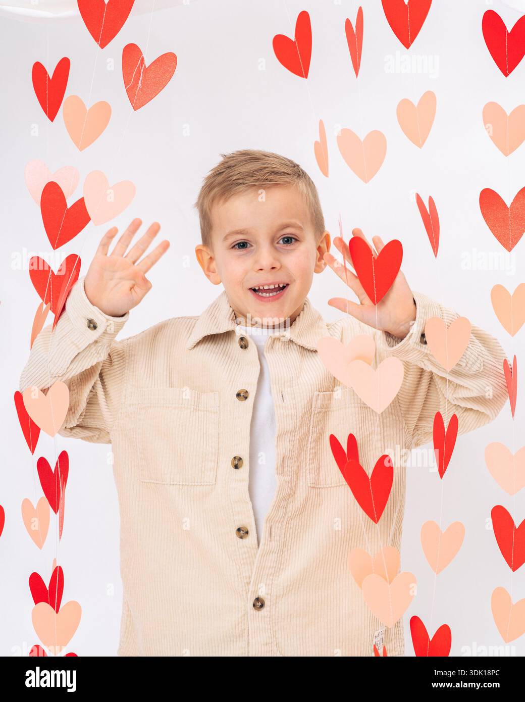 Smiling child waving hands surrounded by red hearts on white background ...