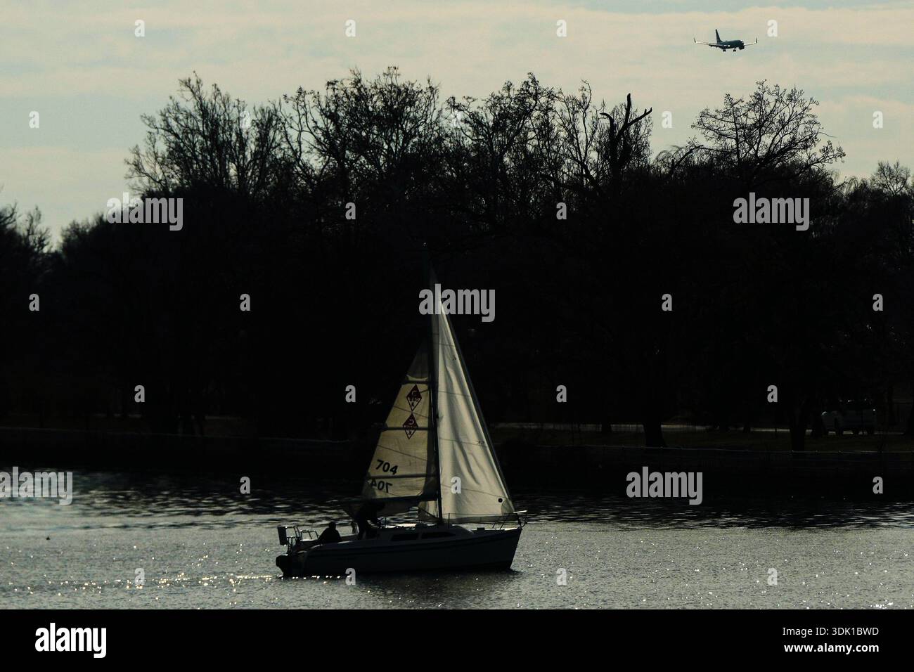 A plane passes a sailboat on the Potomac River while landing at Reagan ...