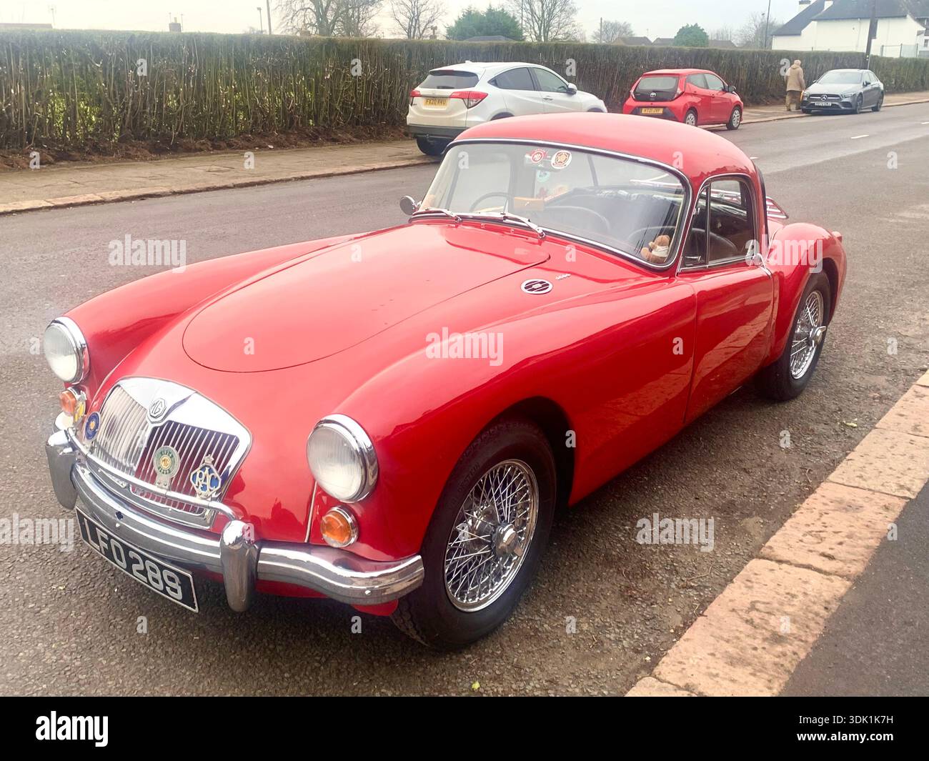 Classic red MG MGA sports car parked roadside in suburban British ...