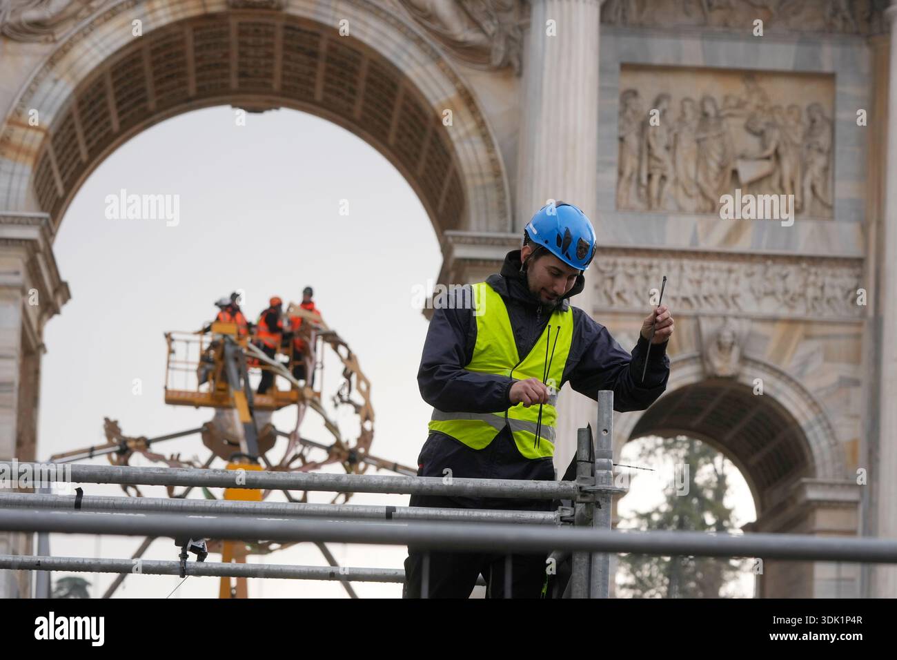 Workers set the Olympics cauldron at the Peace arch in Milan, Italy ...