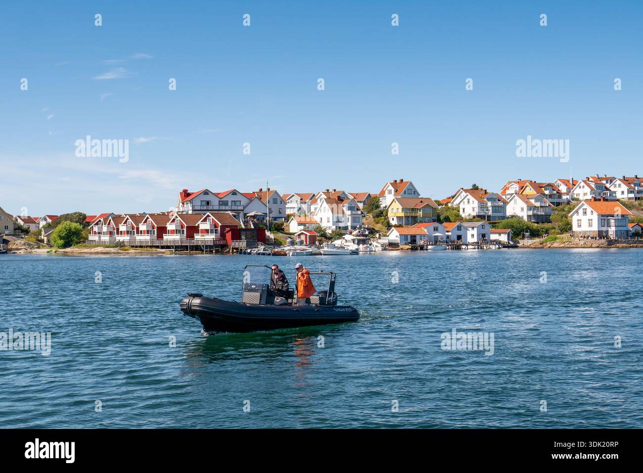 People in RIB boat passing coastal houses of Gullholmen on Härmanö ...