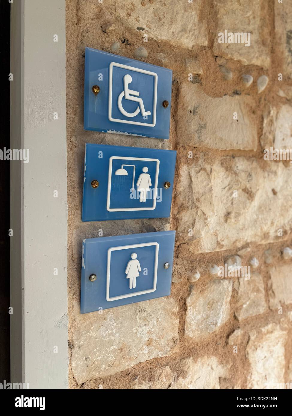 Accessible restroom signs on a stone wall showing symbols for ...
