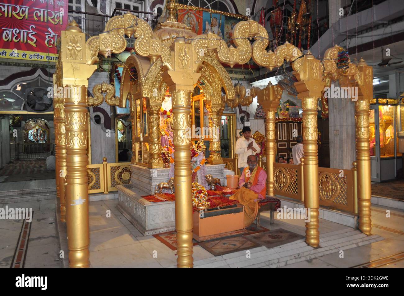 Interior of a Hindu temple with ornate shrine and worshippers in India ...