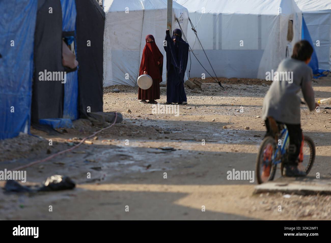 Two women stand among tents at Roj camp, one of the detention ...