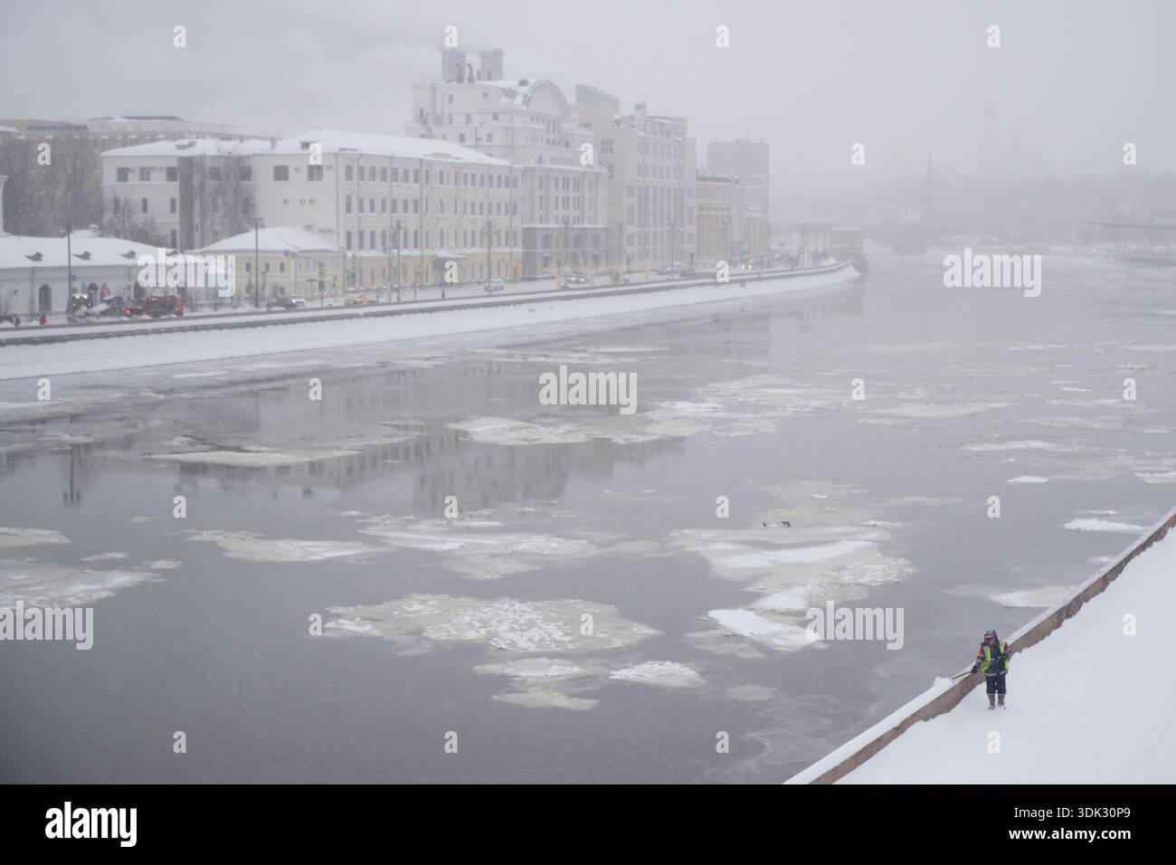 A worker shovels snow at the Moskva River embankment during heavy ...