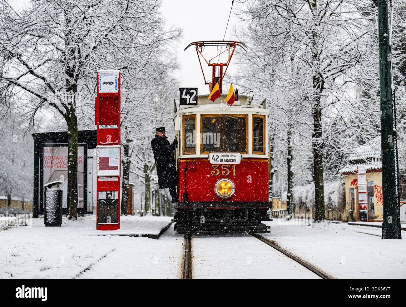 A conductor leans out of the historic tram line No. 42 at the stop ...