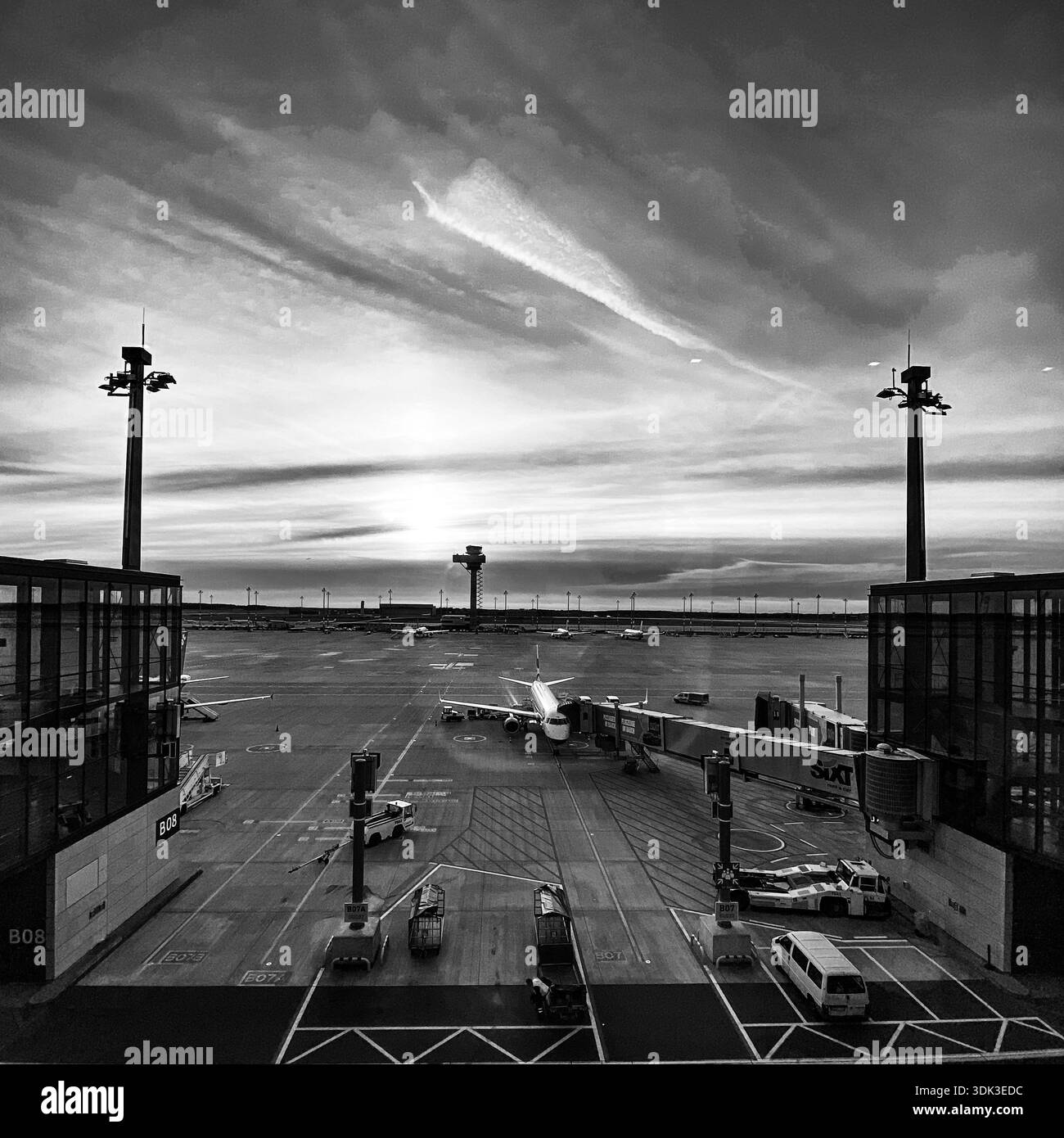 Monochrome view of an airport terminal at sunset, featuring a passenger ...