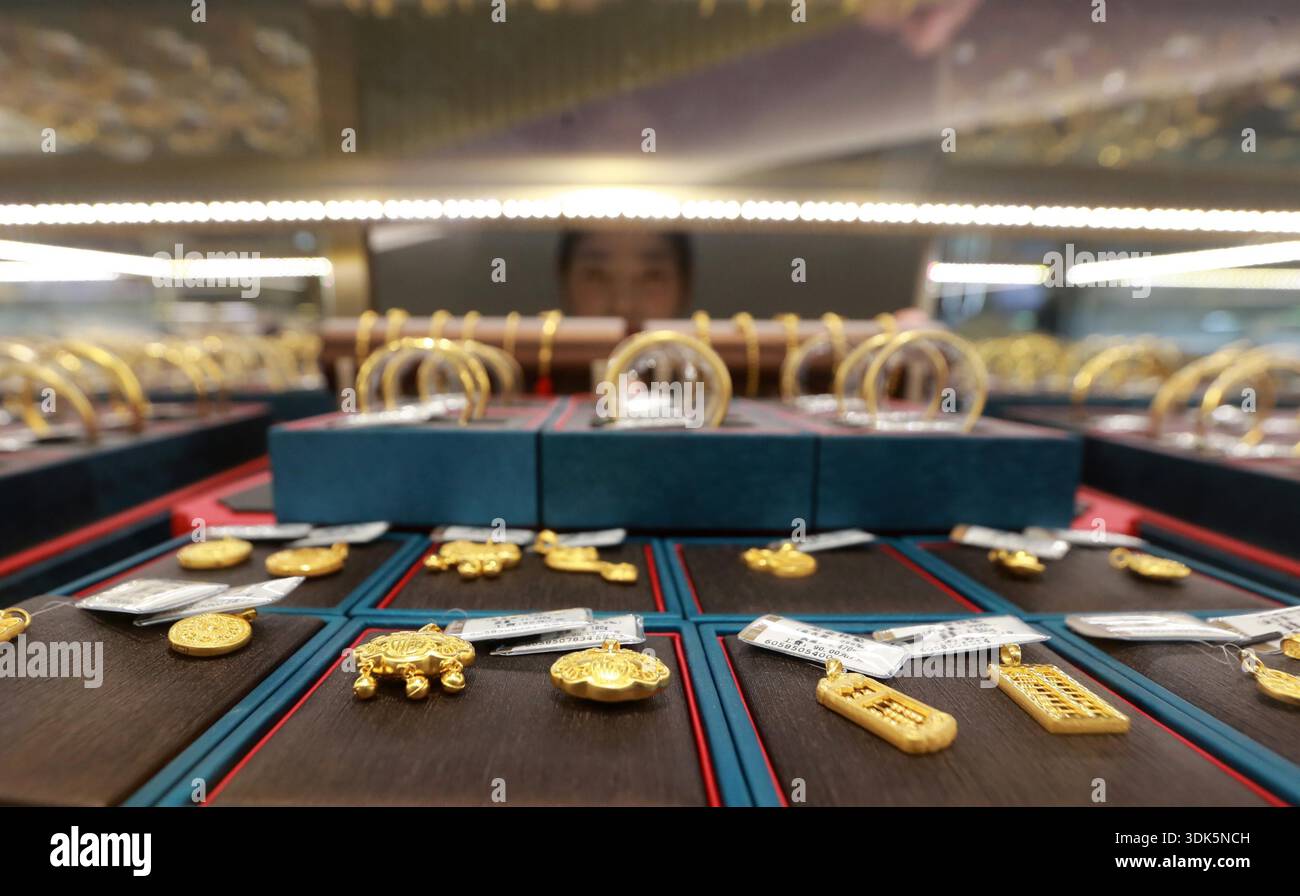 A staff member arranges gold jewelry at a gold store in Yangzhou City ...