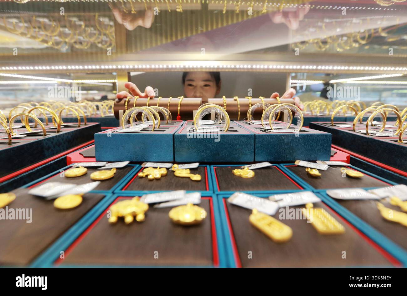 A staff member arranges gold jewelry at a gold store in Yangzhou City ...