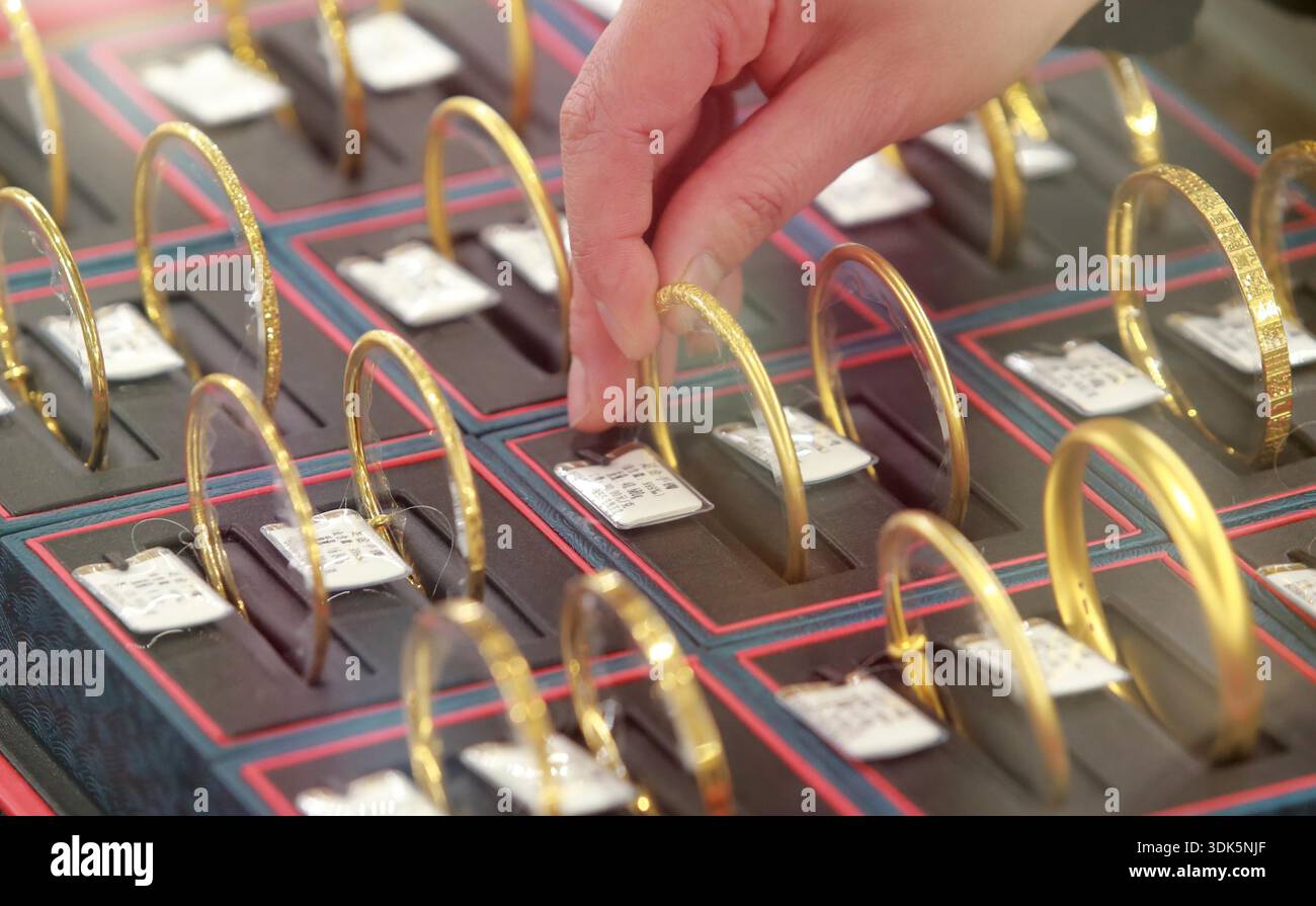 A staff member arranges gold jewelry at a gold store in Yangzhou City ...