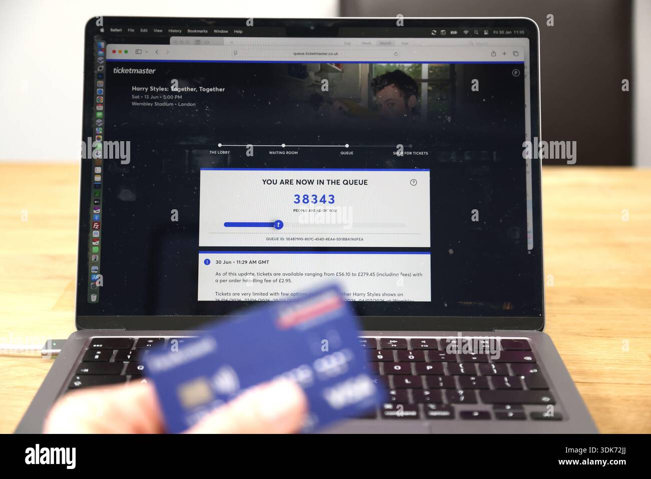 A person holds a credit card as they are in a Ticketmaster queue, for ...