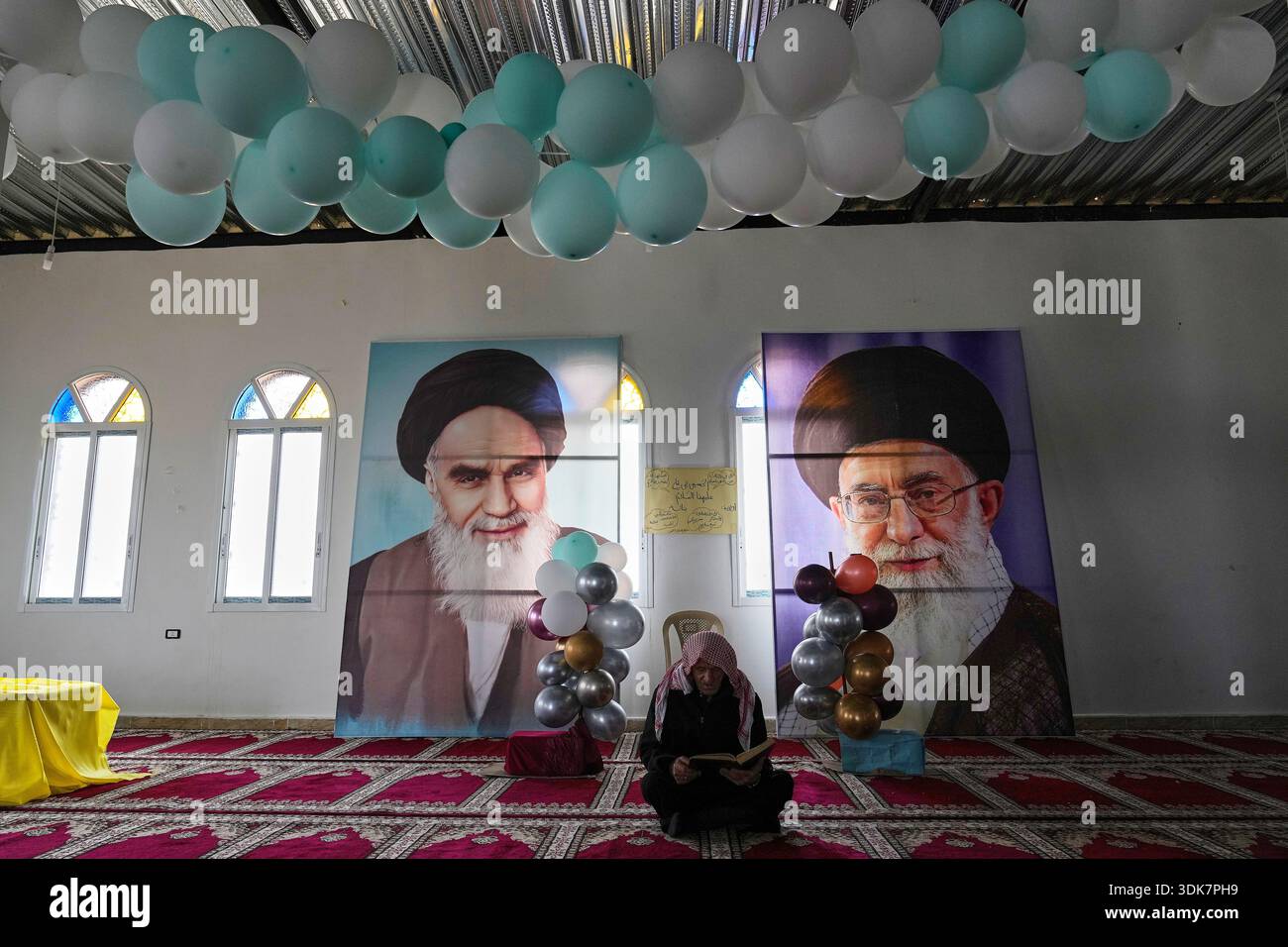 A Syrian Shiite man reads the holy book of Quran in front of portraits ...