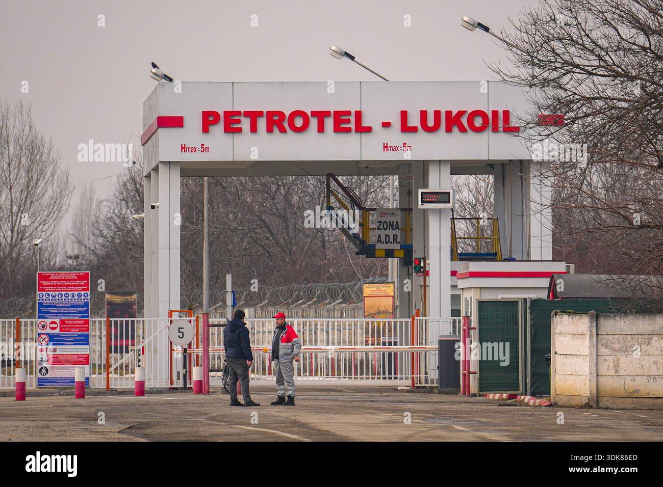 Men stand at one of the entrances of the Petrotel-Lukoil refinery ...