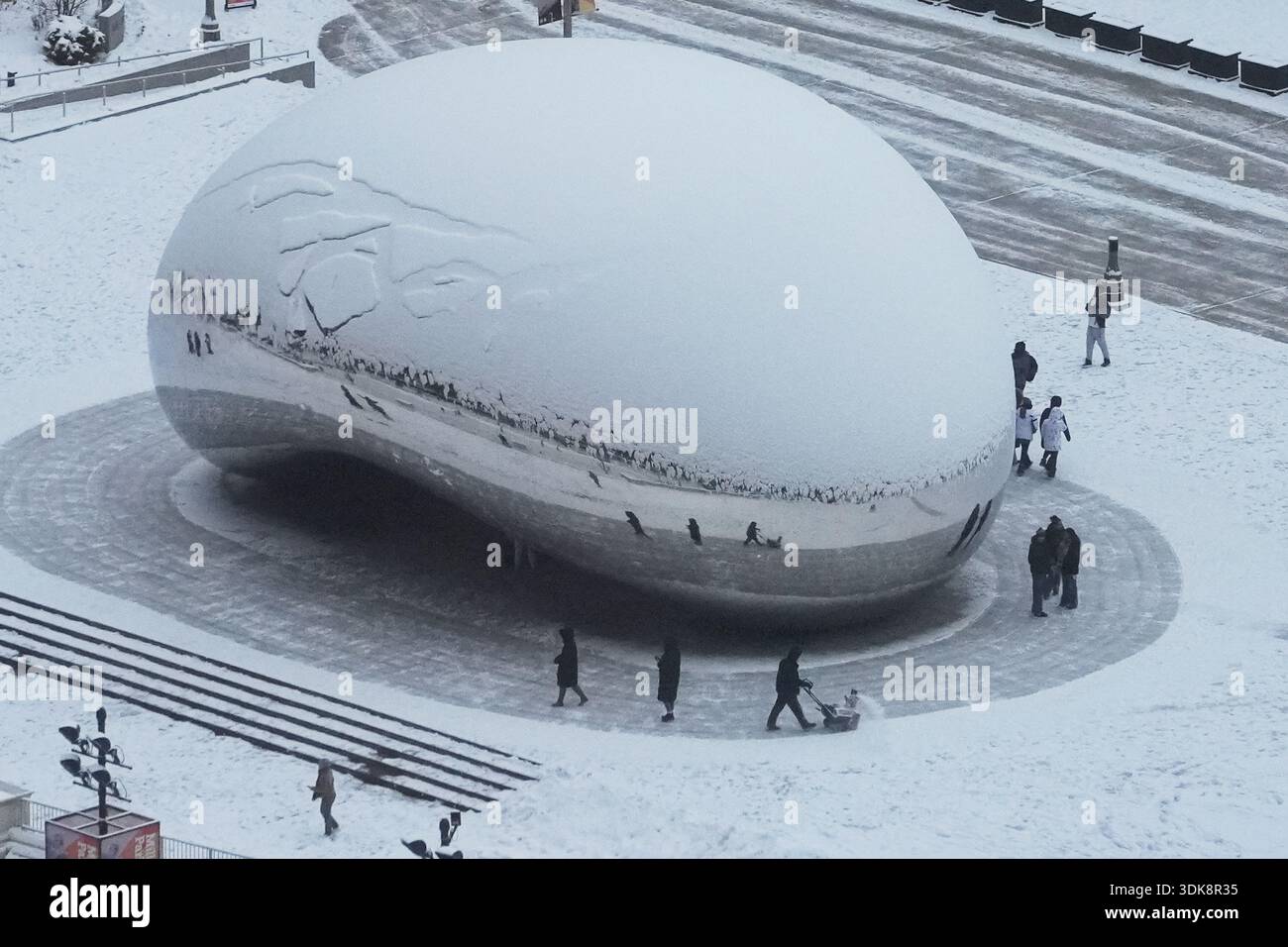 Visitors gather around the snow-covered "Cloud Gate" sculpture, also ...