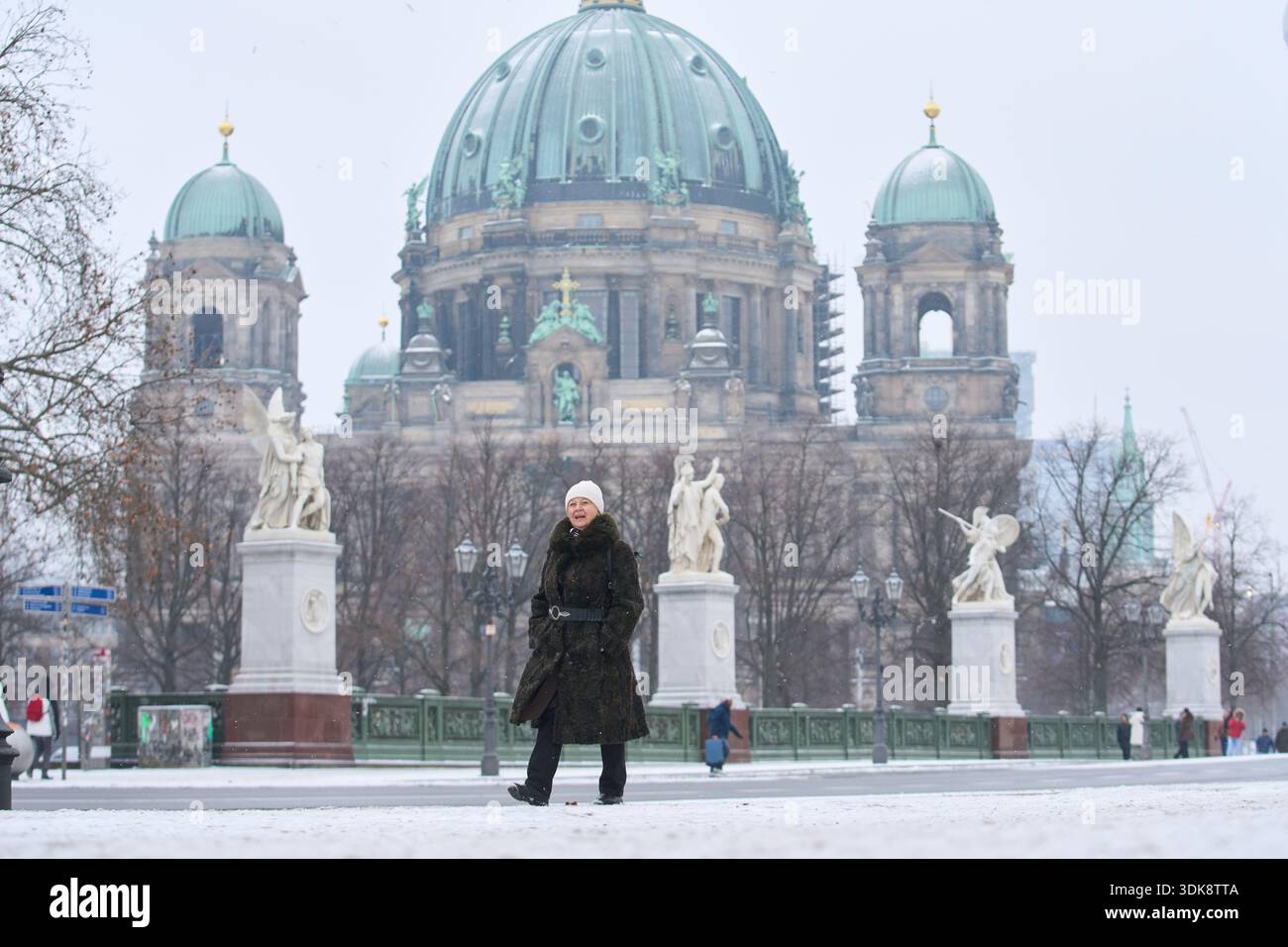 People walk on the sidewalk around the Berlin Cathedral as winter ...