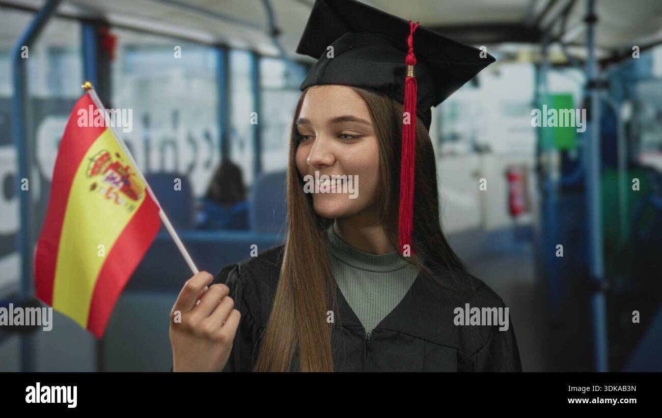 Woman wearing graduation cap and gown holds spanish flag inside street ...