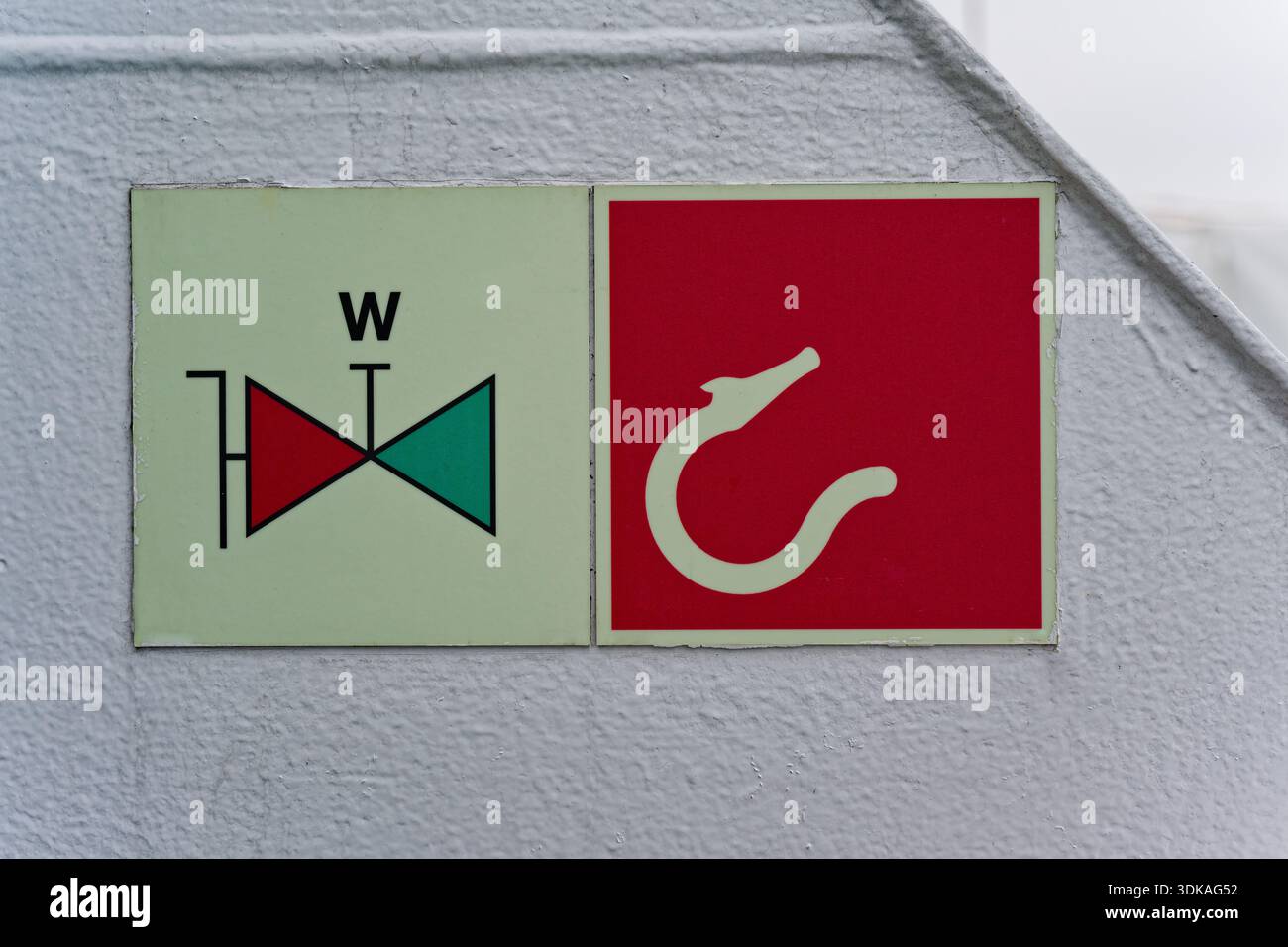 On a white metal ship wall two marine signs are mounted side by side ...