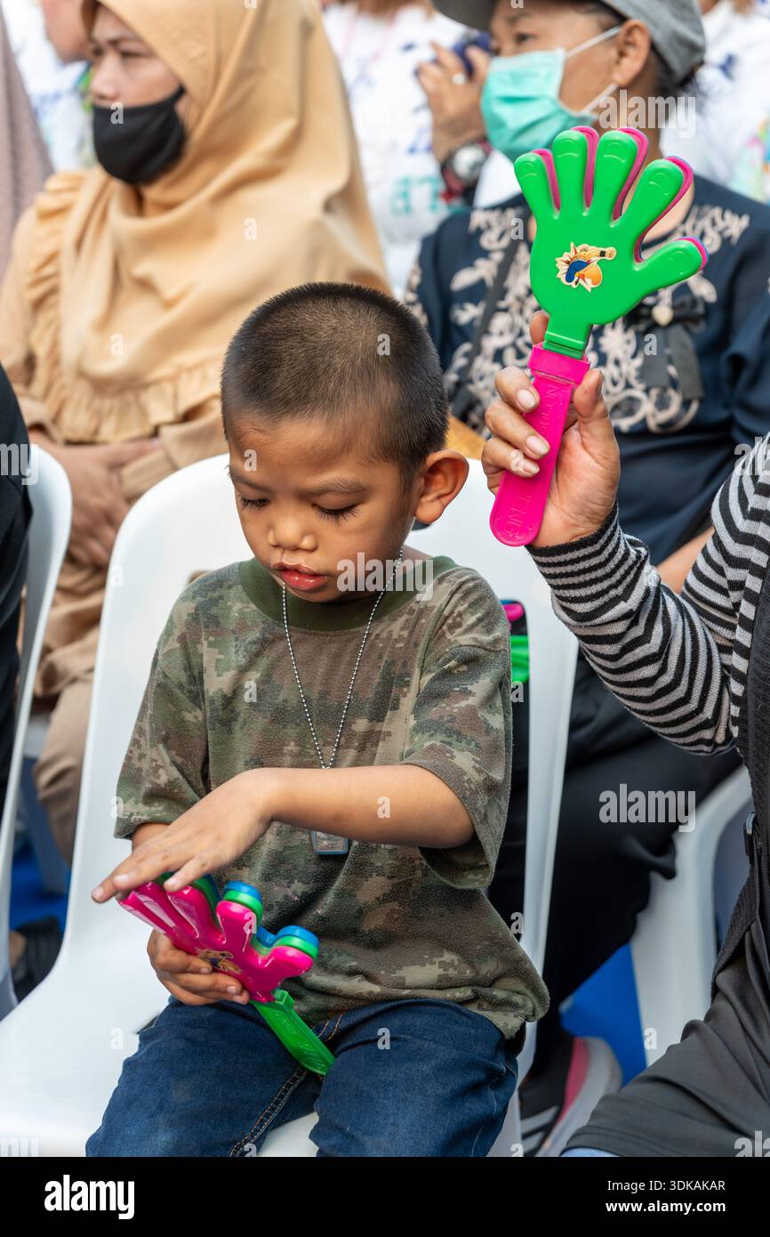 A child holds a plastic hand clapper to show support during a ...