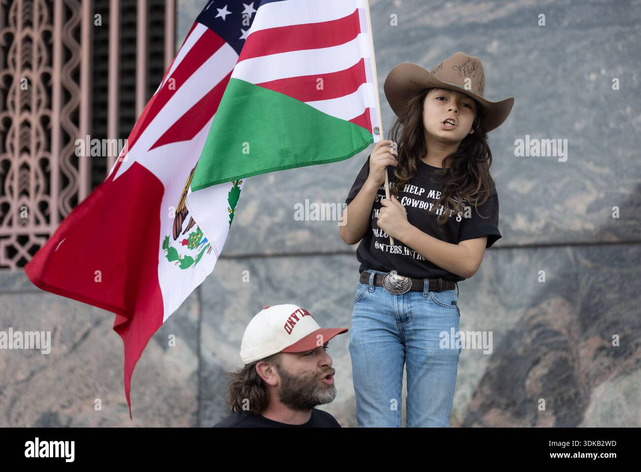 A child stands elevated at an ICE Out protest in Los Angeles, holding a ...