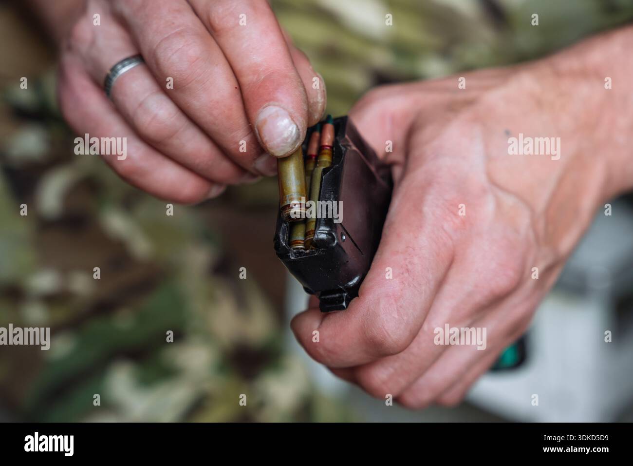 Close-up of soldier hands loading ammunition into a rifle magazine ...
