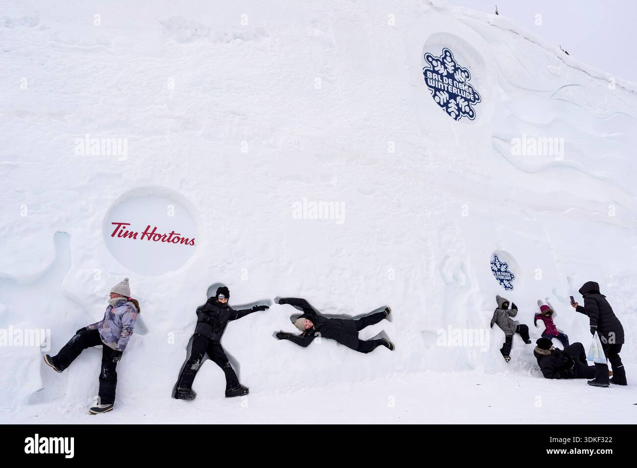 People pose in shapes cut into the snow wall at Snowflake Kingdom at ...